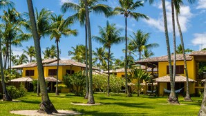 Resort com vários edifícios amarelos, palmeiras e um céu azul límpido.