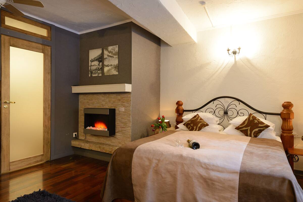 Quarto com lareira, cama com cabeceira e uma porta.