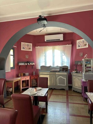 Uma área de refeições com um arco vermelho, um projetor e uma bancada de cozinha.