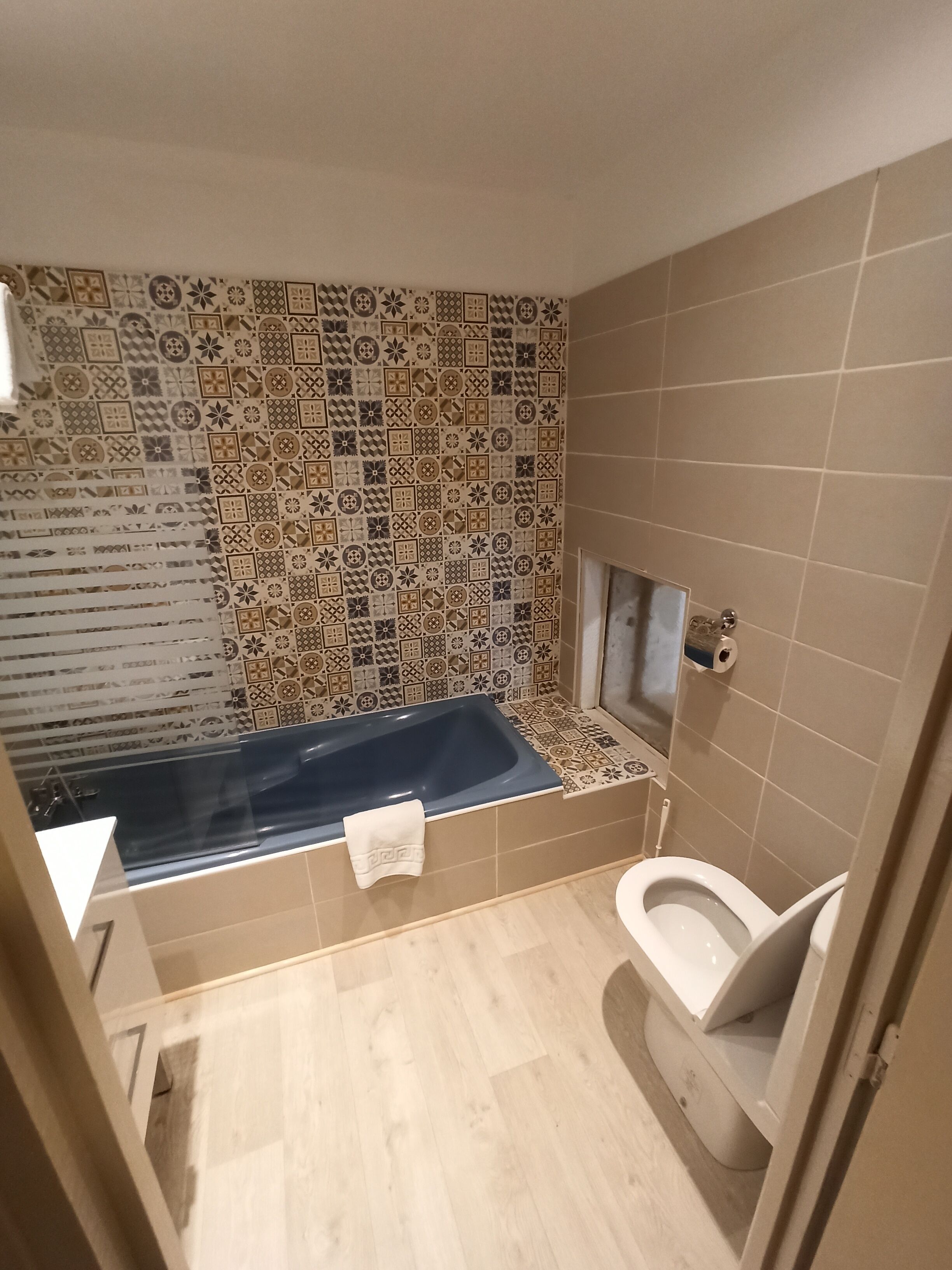 Casa de banho com banheira, sanita e azulejos estampados.