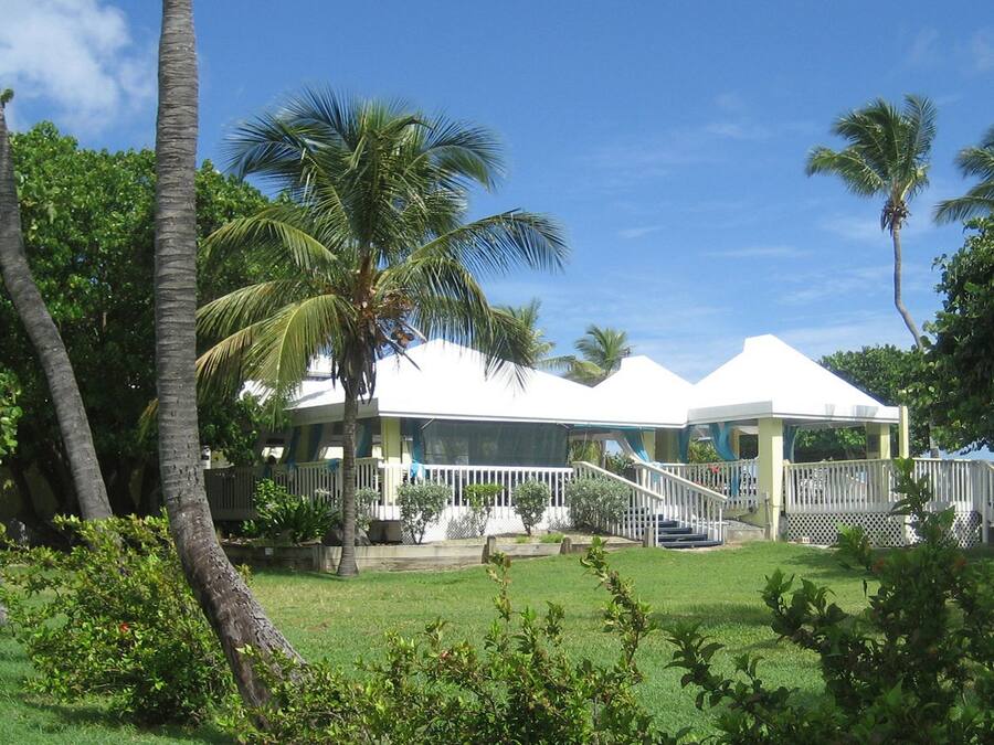 Um resort com um edifício branco, uma área externa coberta e palmeiras.