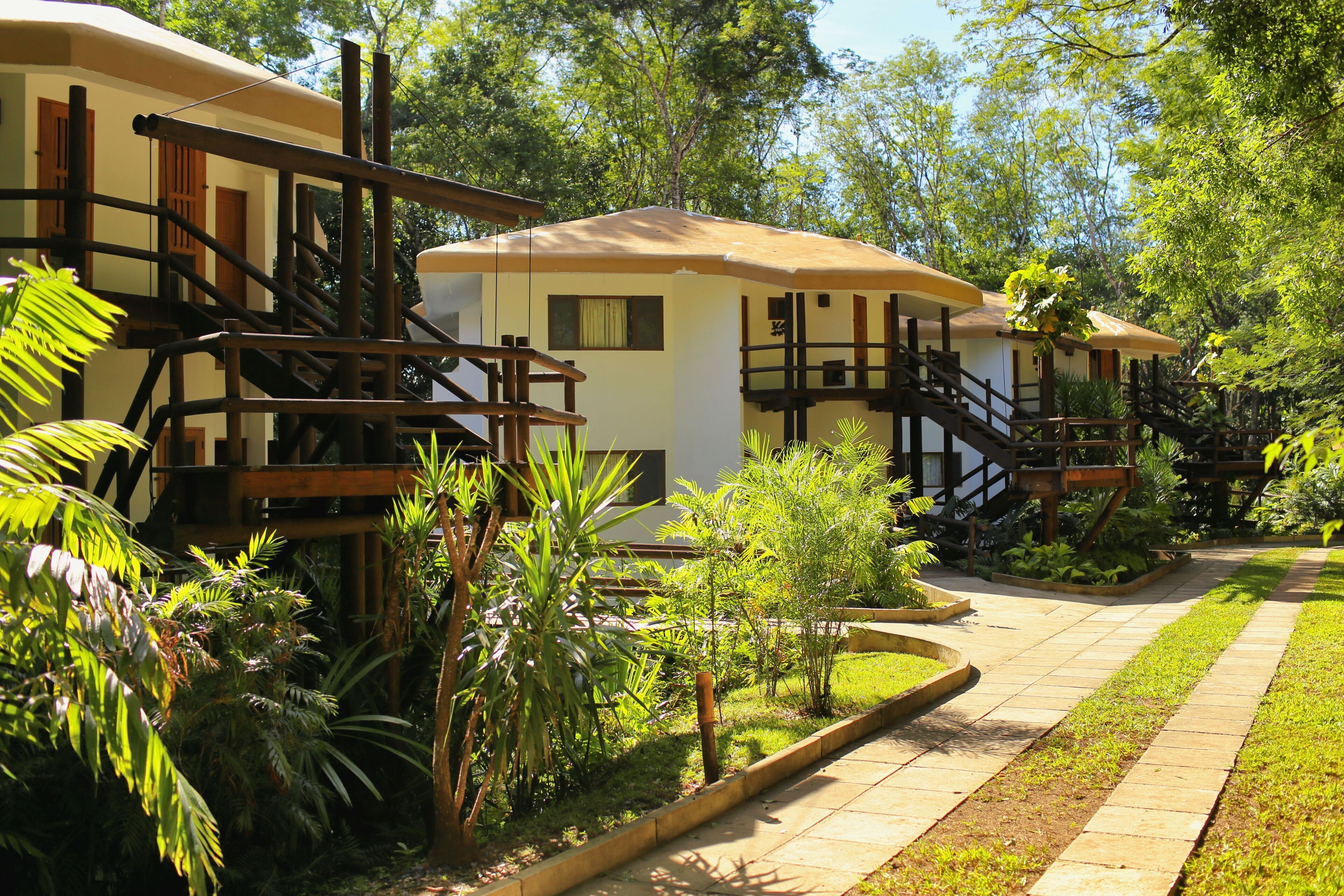 Um resort com vários edifícios no estilo de bangalôs, cada um com uma varanda e uma escadaria que leva ao terraço.