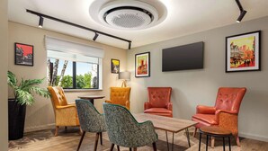 Uma sala de conferência moderna com uma mesa redonda, quatro cadeiras e uma janela grande.