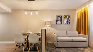 Uma sala de estar moderna com um sofá, mesa de jantar, cadeiras e um abajur.