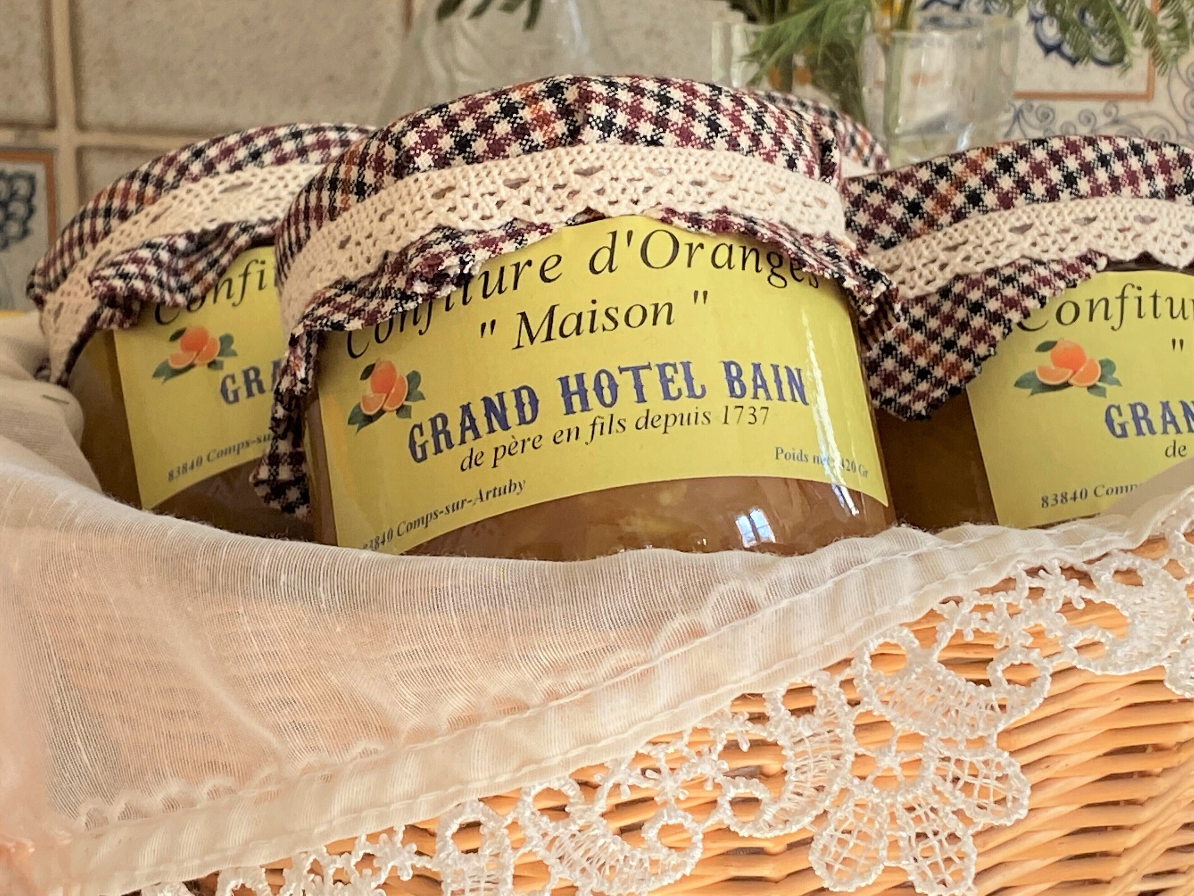 Potes de marmelada de laranja 'Maison' com etiquetas, sobre um bordado de renda.