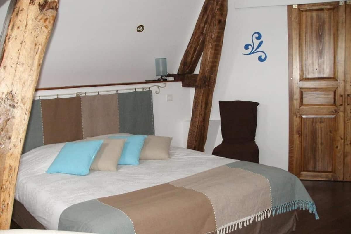 Quarto com uma cama, porta de madeira e parede com detalhe decorativo.