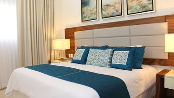 Quarto de hotel com uma cama grande, cabeceira de madeira e duas luminárias de cabeceira.