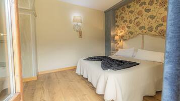 Quarto com cama, mesa de cabeceira, luminária na parede e janela com vista para o exterior.