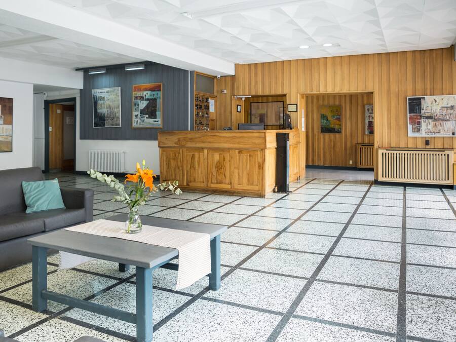 Um hall de entrada com balcão de recepção, um sofá, uma mesa de centro e piso revestido de azulejos.