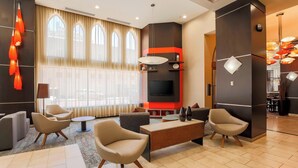 Um lobby de hotel moderno com uma ampla área de estar, uma TV de tela plana e uma lareira.