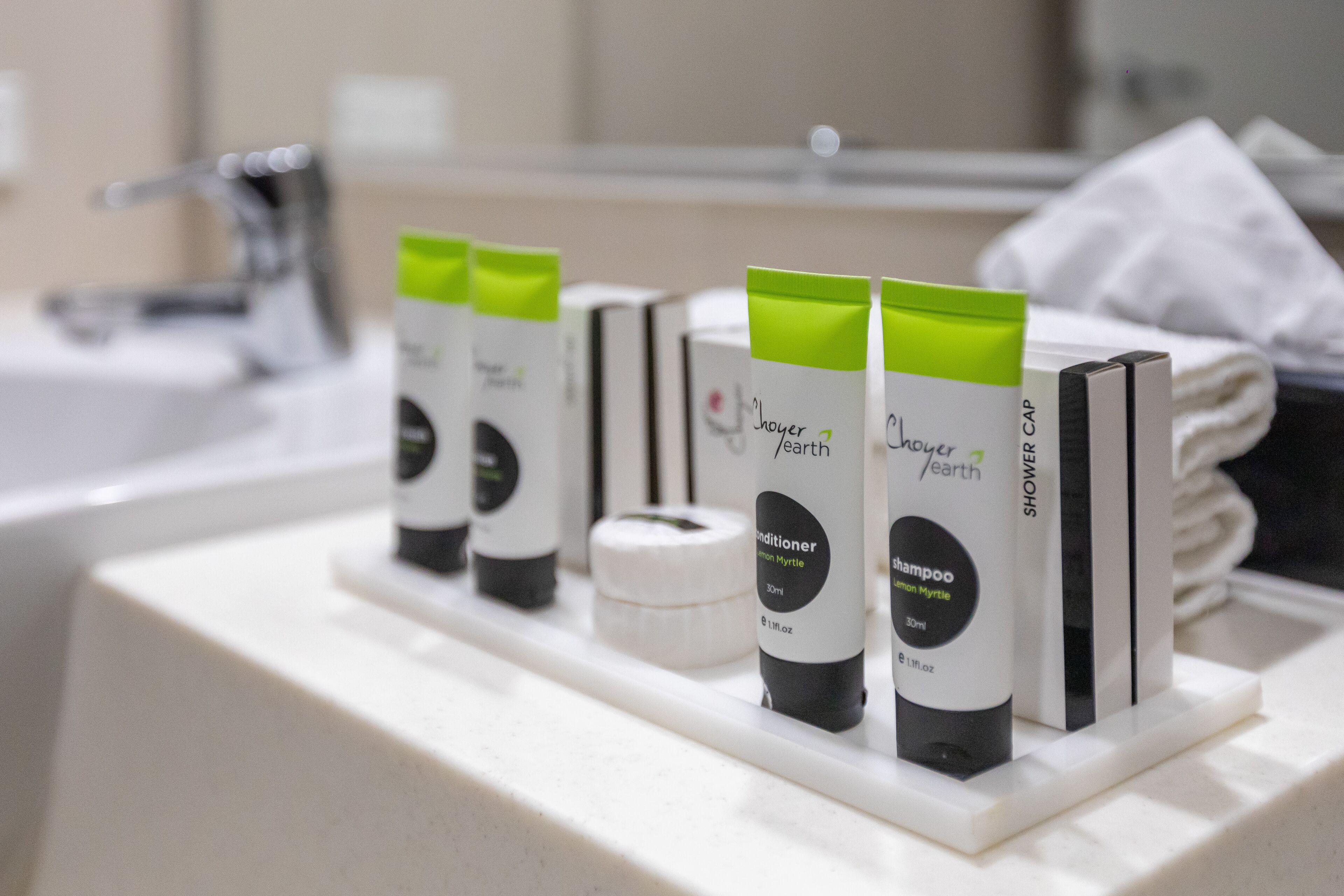 Uma prateleira no banheiro com artigos de higiene pessoal, incluindo touca de banho, condicionador e shampoo.