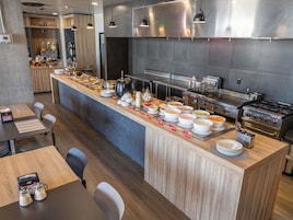 Cozinha moderna com espaço para buffet, incluindo diversos recipientes de comida e uma máquina de café.