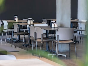 Uma área de refeições moderna, com mesas e cadeiras, algumas com temperos.