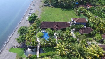 Vista aérea de um resort com piscina, palmeiras e uma praia.