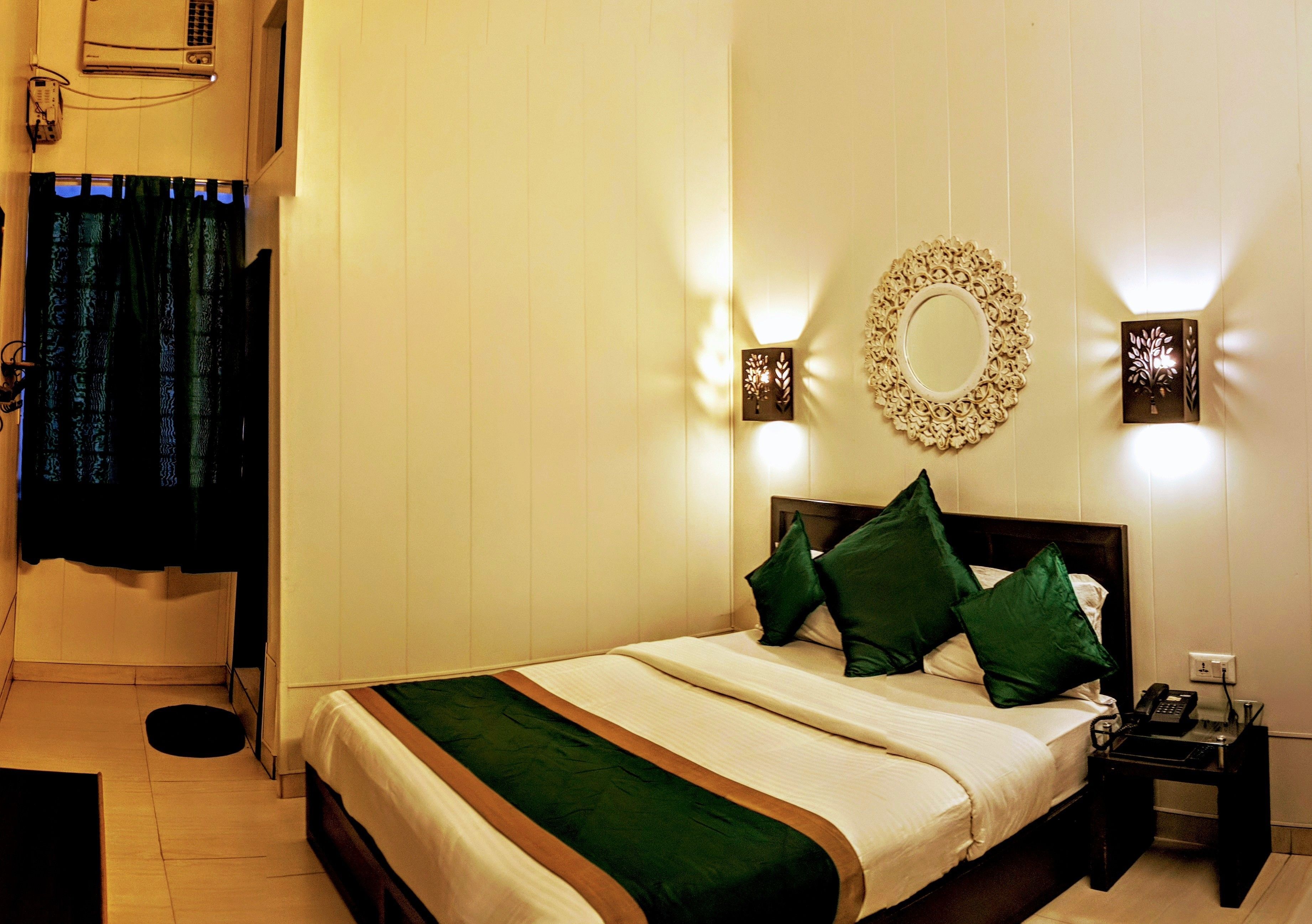 Quarto de hotel com cama, mesa de cabeceira e luminárias fixadas na parede.
