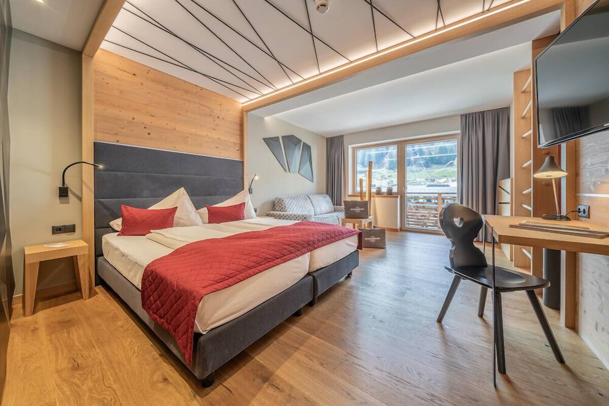 Quarto de hotel moderno com uma cama grande, uma escrivaninha e uma televisão.