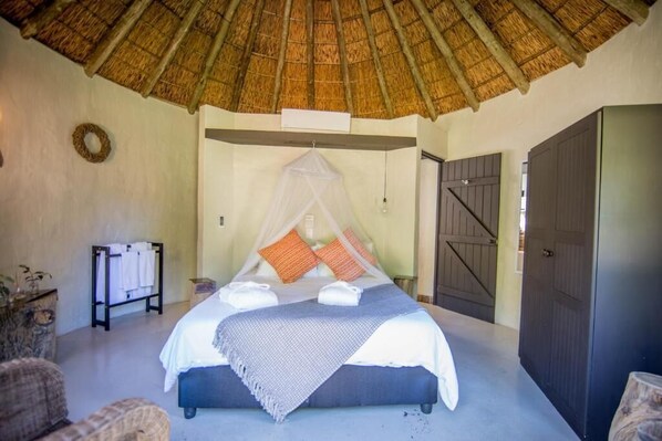 Quarto com cama, mosquiteiro, guarda-roupa e porta-toalhas.