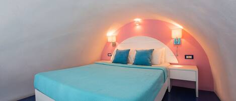 Quarto com cama, mesas de cabeceira e luminárias fixadas na parede.