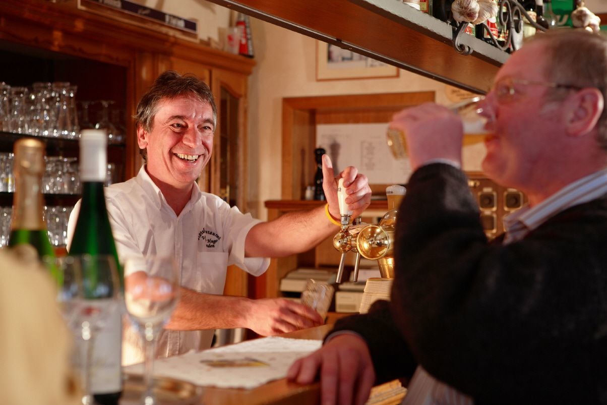 Um bar com um bartender servindo uma bebida a um cliente.