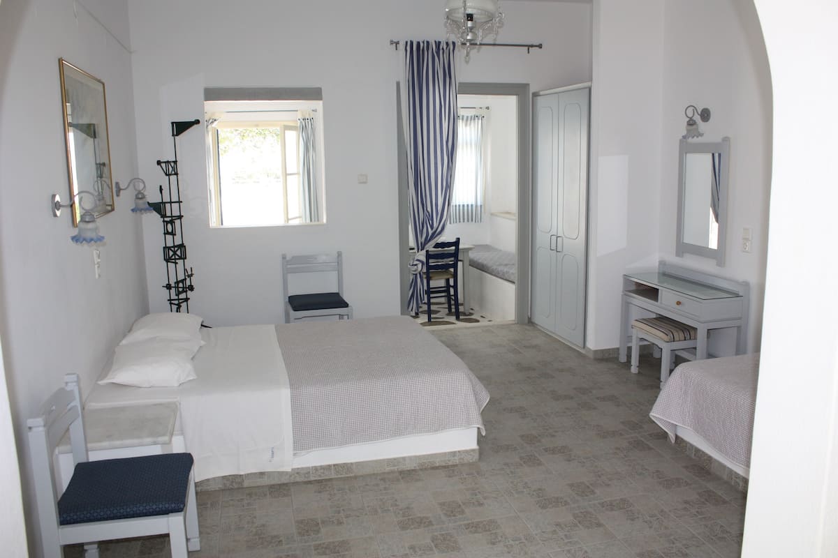 Um quarto com cama, escrivaninha, cadeira e guarda-roupa.