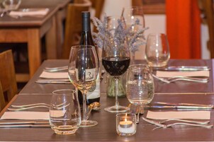 Uma mesa de jantar posta com copos de vinho, uma garrafa e uma vela.