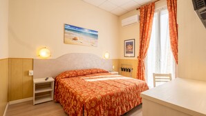 Quarto com cama, mesa de cabeceira e escrivaninha.
