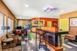 Um saguão de hotel com área de bar, assentos e balcão de recepção.