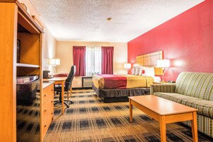 Quarto de hotel com cama, sofá, escrivaninha e cadeira.