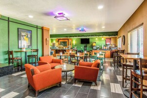 Um restaurante com assentos laranja, paredes verdes e piso ladrilhado.
