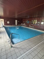Uma piscina interior com placas indicando proibição de mergulho, de fumar e proibição de mergulho na borda da piscina.