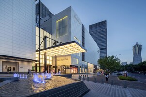 Uma loja moderna da Louis Vuitton, com uma entrada destacada e um elemento aquático em frente.