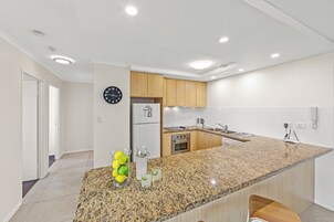 Uma cozinha moderna com bancadas de granito, armários de madeira, uma geladeira e uma pia.