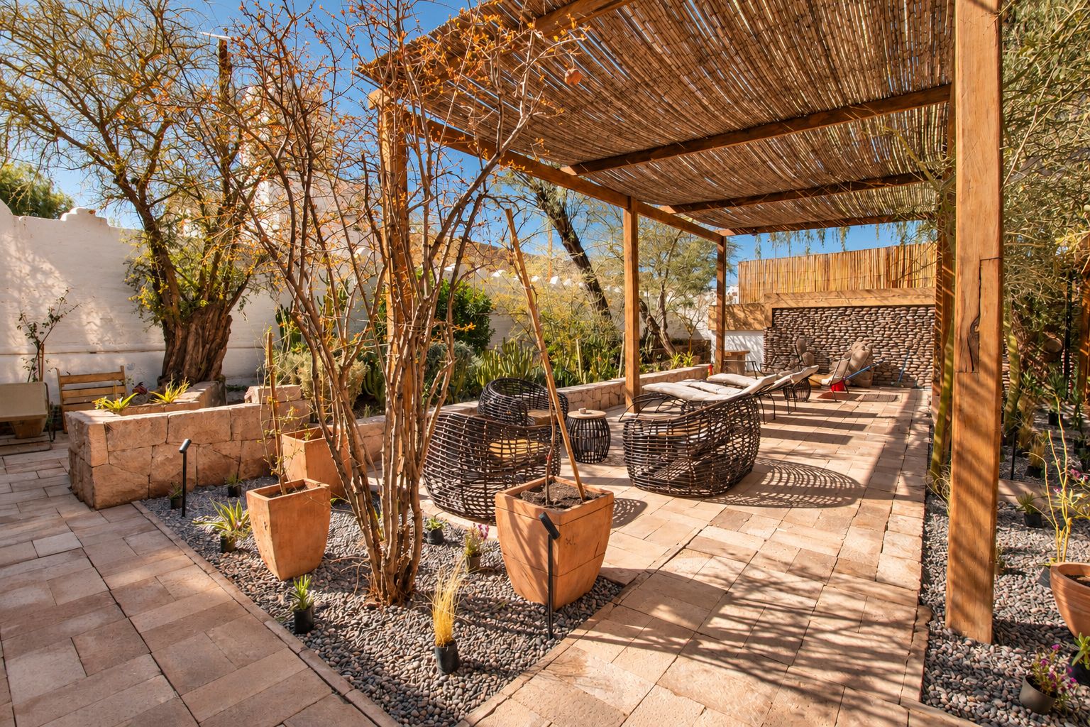 Um pátio externo com pérgola, área de estar e vasos de plantas.
