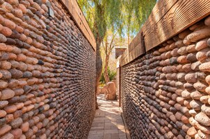 Um caminho estreito ladeado por paredes construídas com pedras grandes e arredondadas.