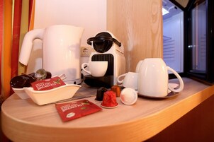 Mesa de madeira com cafeteira, chávenas e saquinhos de chá.