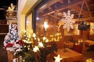 Um restaurante acolhedor com interiores em madeira, luzes em formato de estrela e um enfeite de floco de neve.