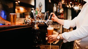 Um bartender servindo cerveja em um copo no balcão.
