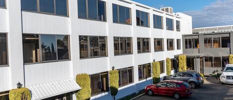 Um edifício moderno com várias janelas e um estacionamento.
