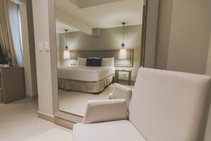 Quarto de hotel com cama, mesas de cabeceira, uma cadeira e um espelho.