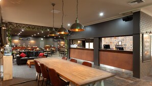 Um restaurante moderno com uma longa mesa de madeira, diversas opções de assento e um balcão.