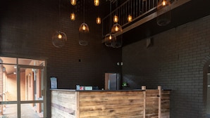 Uma área de recepção com balcão de madeira, luminárias pendentes e parede de tijolos.