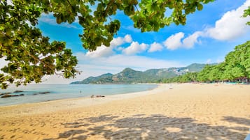 Na praia, areia branca, guarda-sóis, toalhas de praia