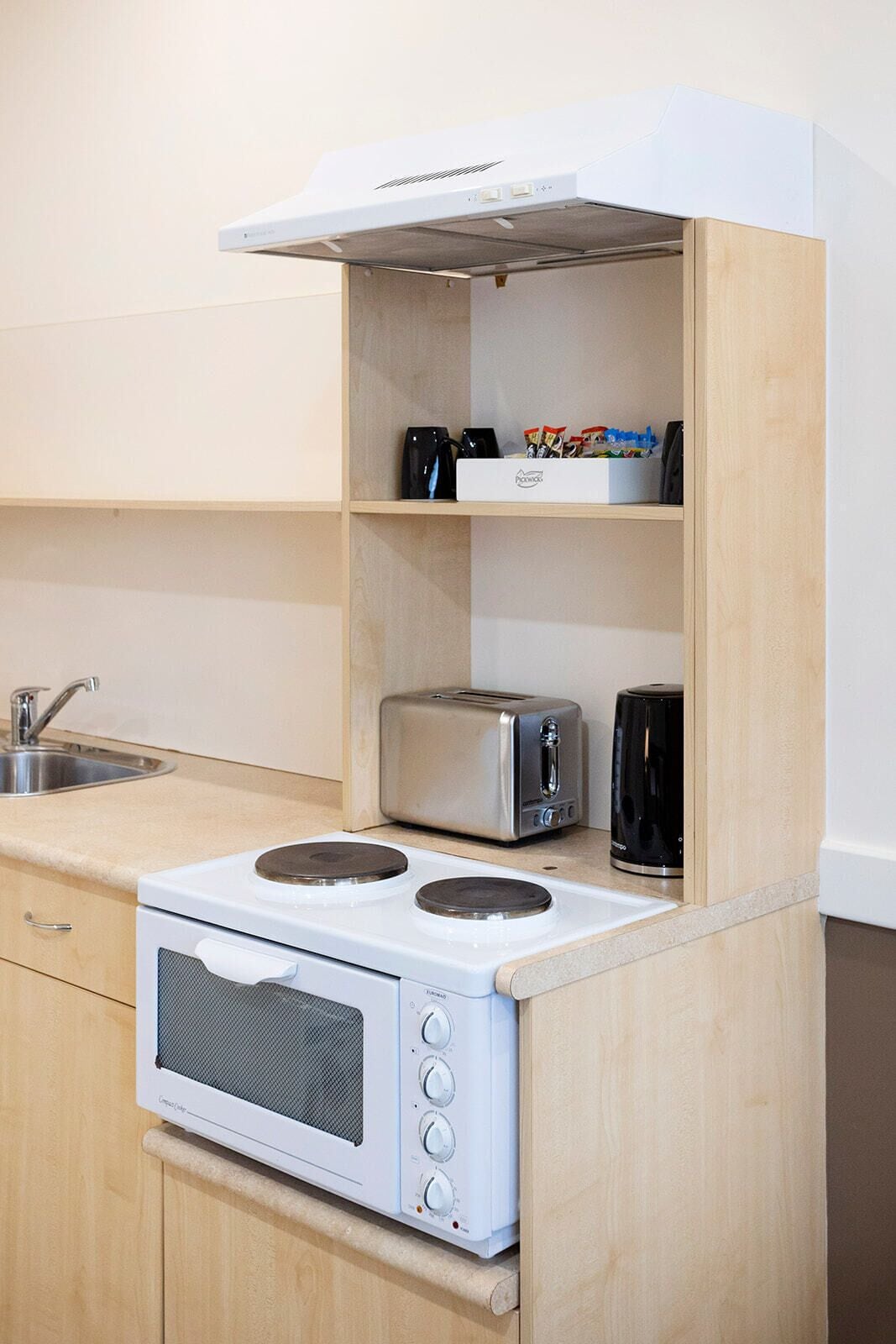 Uma cozinha compacta equipada com fogão, torradeira e cafeteira.
