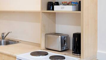 Uma cozinha compacta equipada com fogão, torradeira e cafeteira.