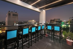 Um bar no terraço com várias cadeiras e um vaso de planta.