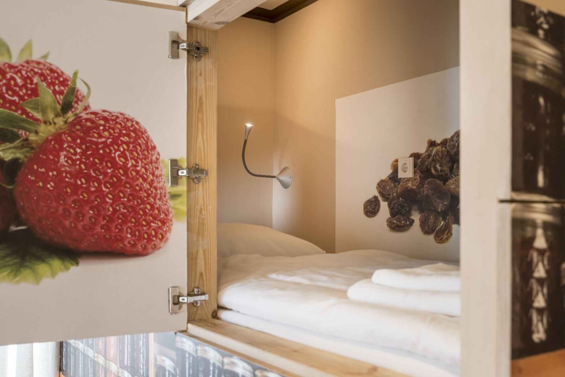 Quarto com estrutura de cama de madeira, colchão branco e luminária fixada na parede.