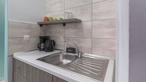 Uma cozinha moderna com uma pia de aço inoxidável, uma cafeteira e uma prateleira com potes.