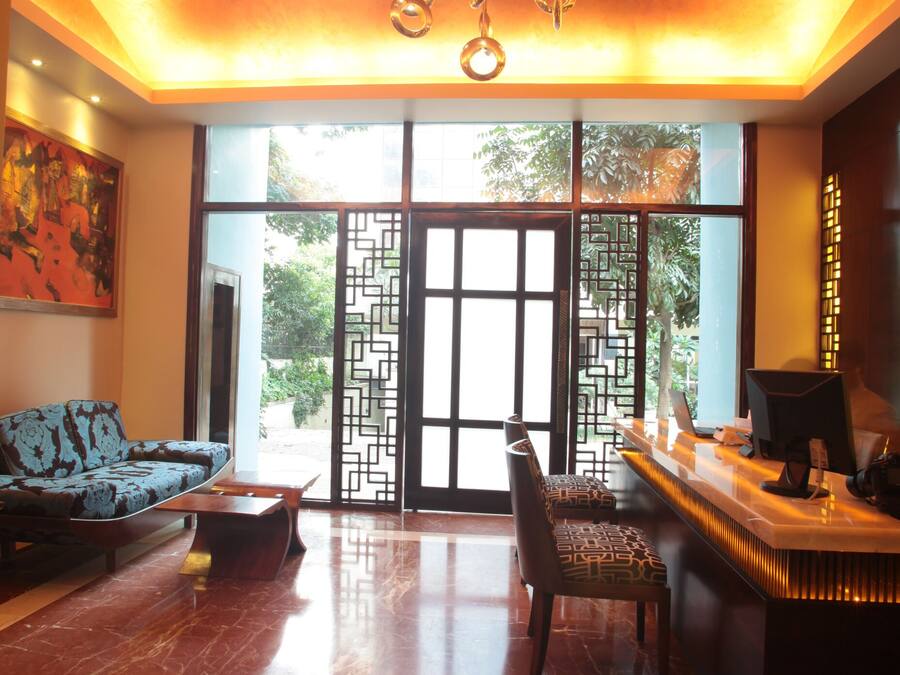 Um hall amplo com piso de mármore, um sofá, uma mesa de escritório e uma grande janela com vista para o verde.