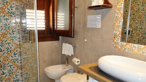 Casa de banho com bidé, sanita e uma grande pia.