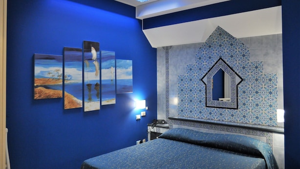 Quarto com decoração azul, incluindo uma cama, obras de arte e um claraboia.
